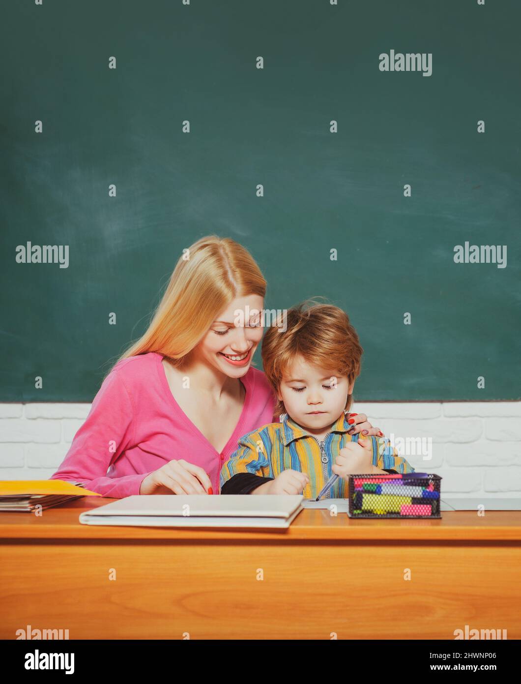 Preschool teacher teaching little student school boy in a classroom ...