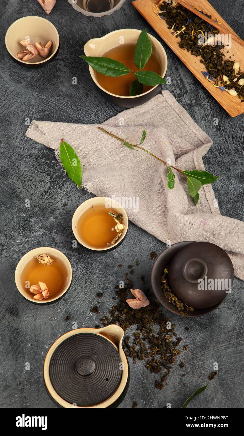 Asian tea set on dark background. Plant leaves, natural herbal tea ...