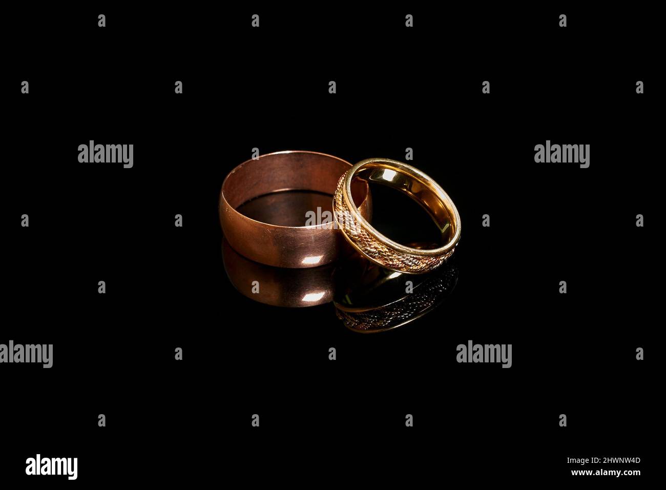 Two gold wedding rings on a black background Stock Photo - Alamy