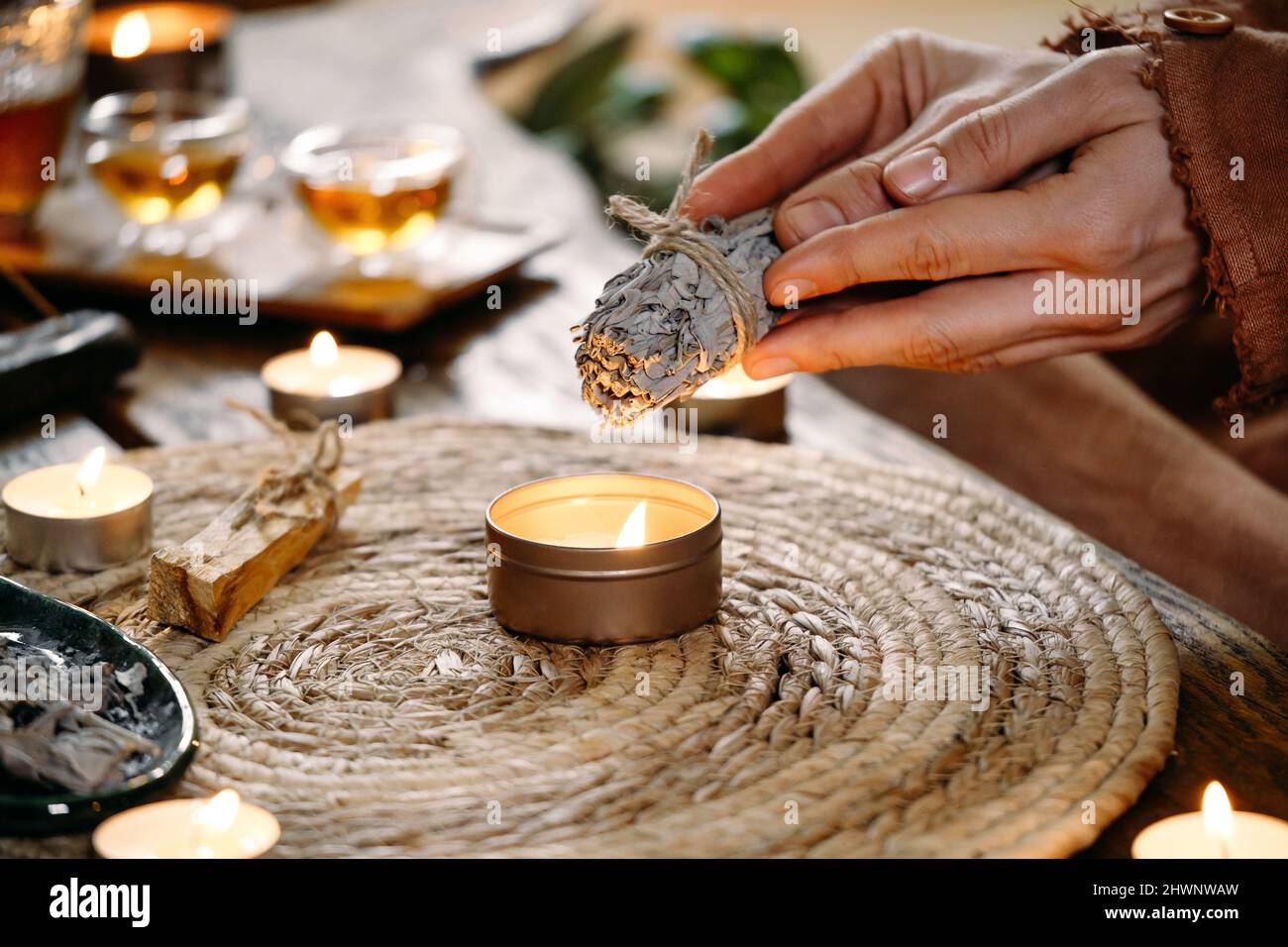 Woman hands burning white sage, before ritual on the table with candles ...