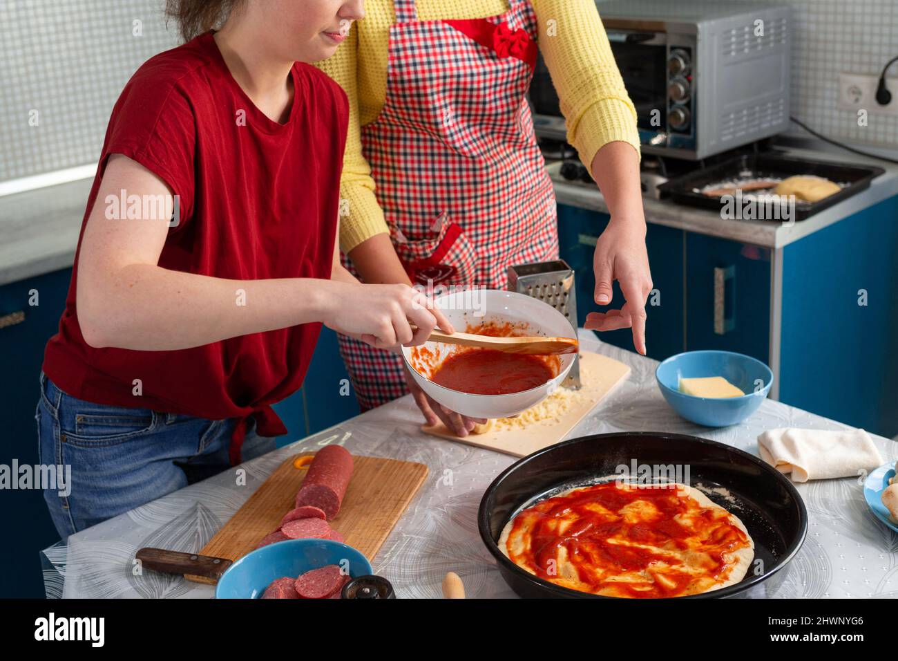 Caucasian women prepare food together in the kitchen. They spread the ...