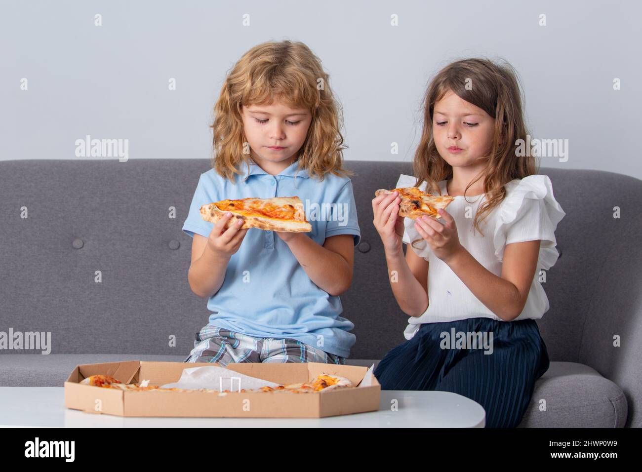 Cute little kids boy and girl eating Pizza at home. Children holding a ...