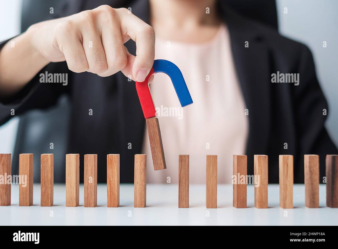 Business woman hand holding magnet and pulling man wooden figure from ...