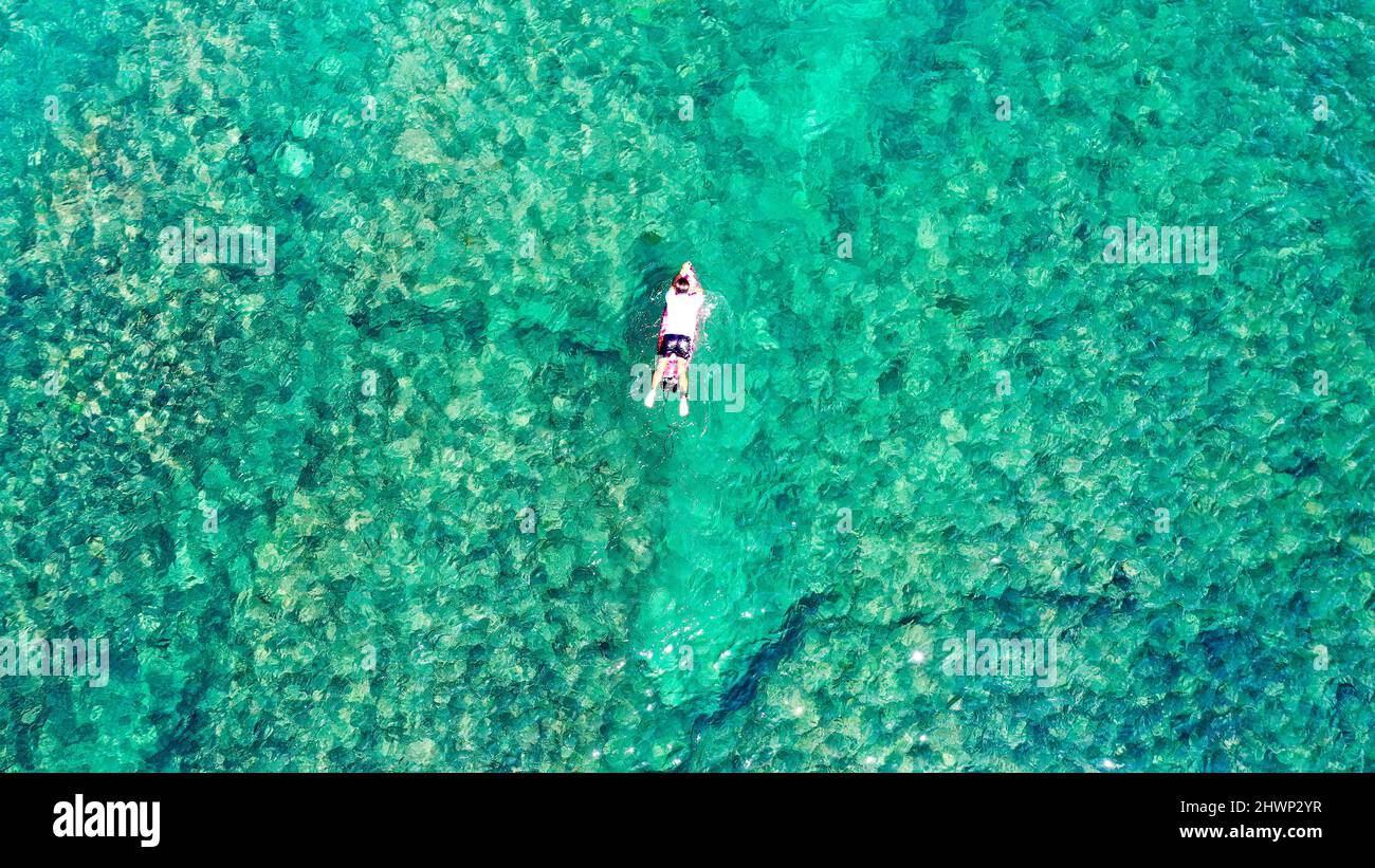 A lone surfer sits on his surfboard waiting for a wave like a spec in ...