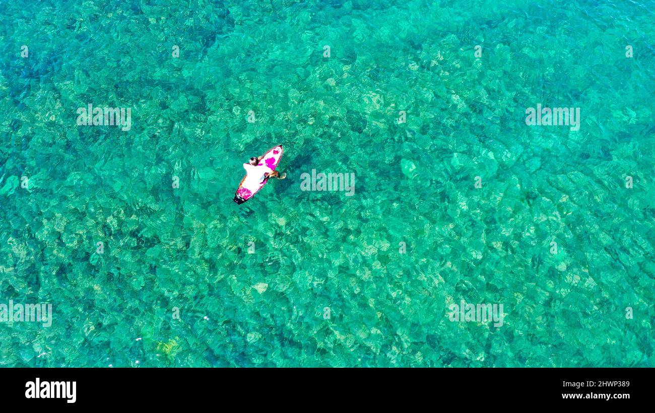 A lone surfer sits on his surfboard waiting for a wave like a spec in ...