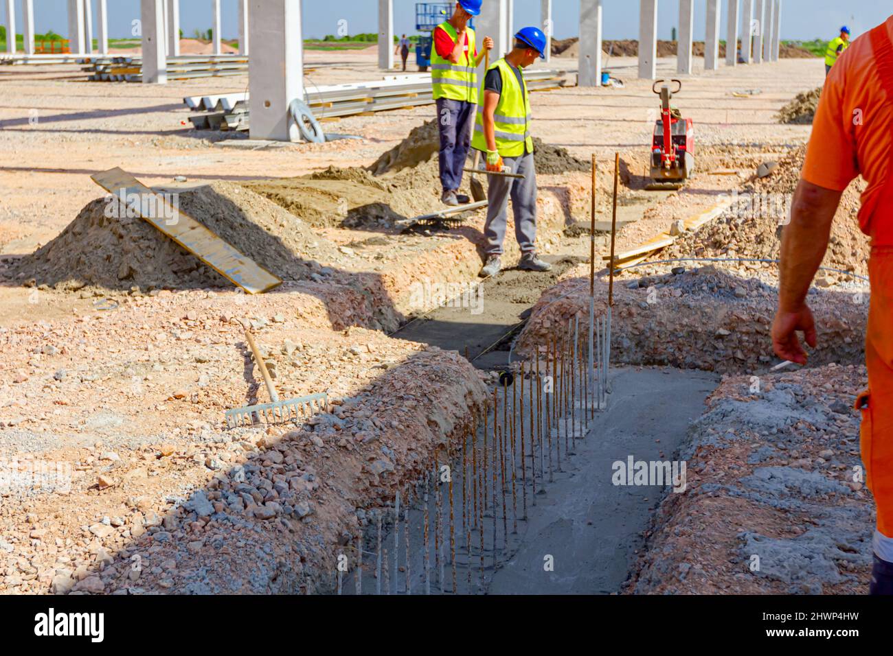 Mason is using a trowel to align first level of the concrete foundation ...