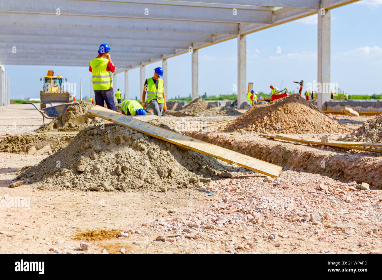 Wooden plank is placed on heap of sand at construction site. Riggers ...