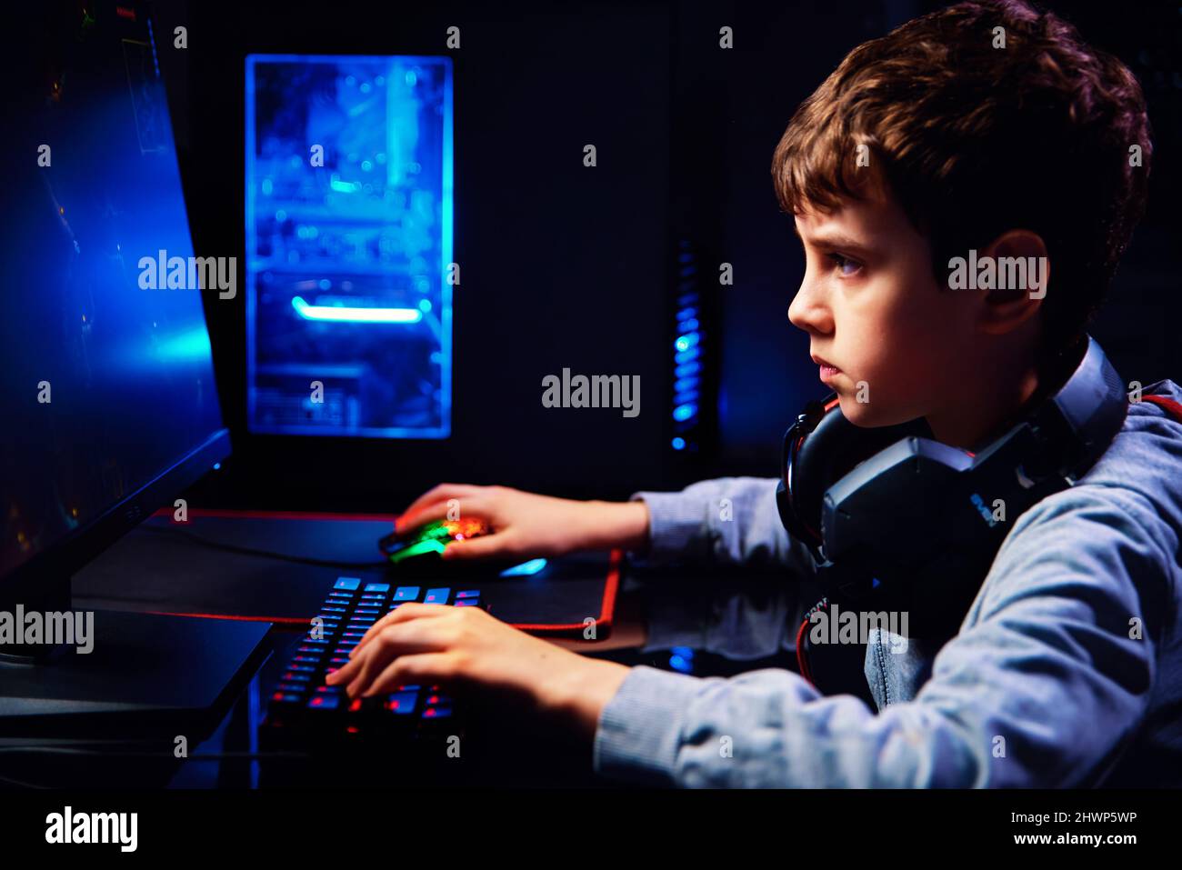Teenager boy play computer video game in dark room, use neon colored ...