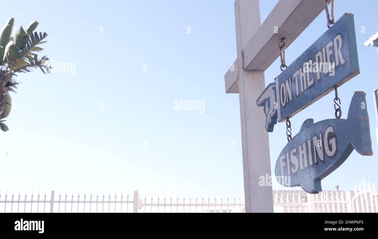 Fishing on pier wooden blue sign, California ocean beach, USA. Coast ...