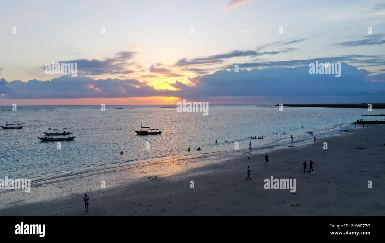 Sunset over ocean waves wash sand beach. Aerial sun set above mountain ...