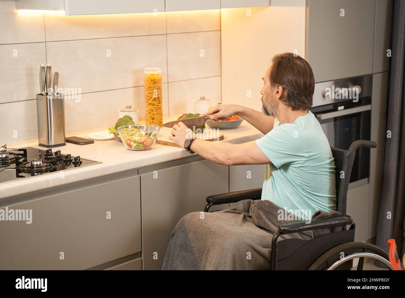 Adult man in a wheelchair cutting vegetables with a knife Stock Photo ...
