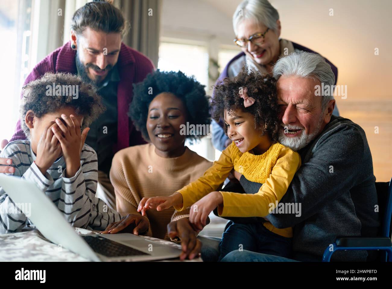 Happy multi-generation family gathering around notebbok and having fun ...
