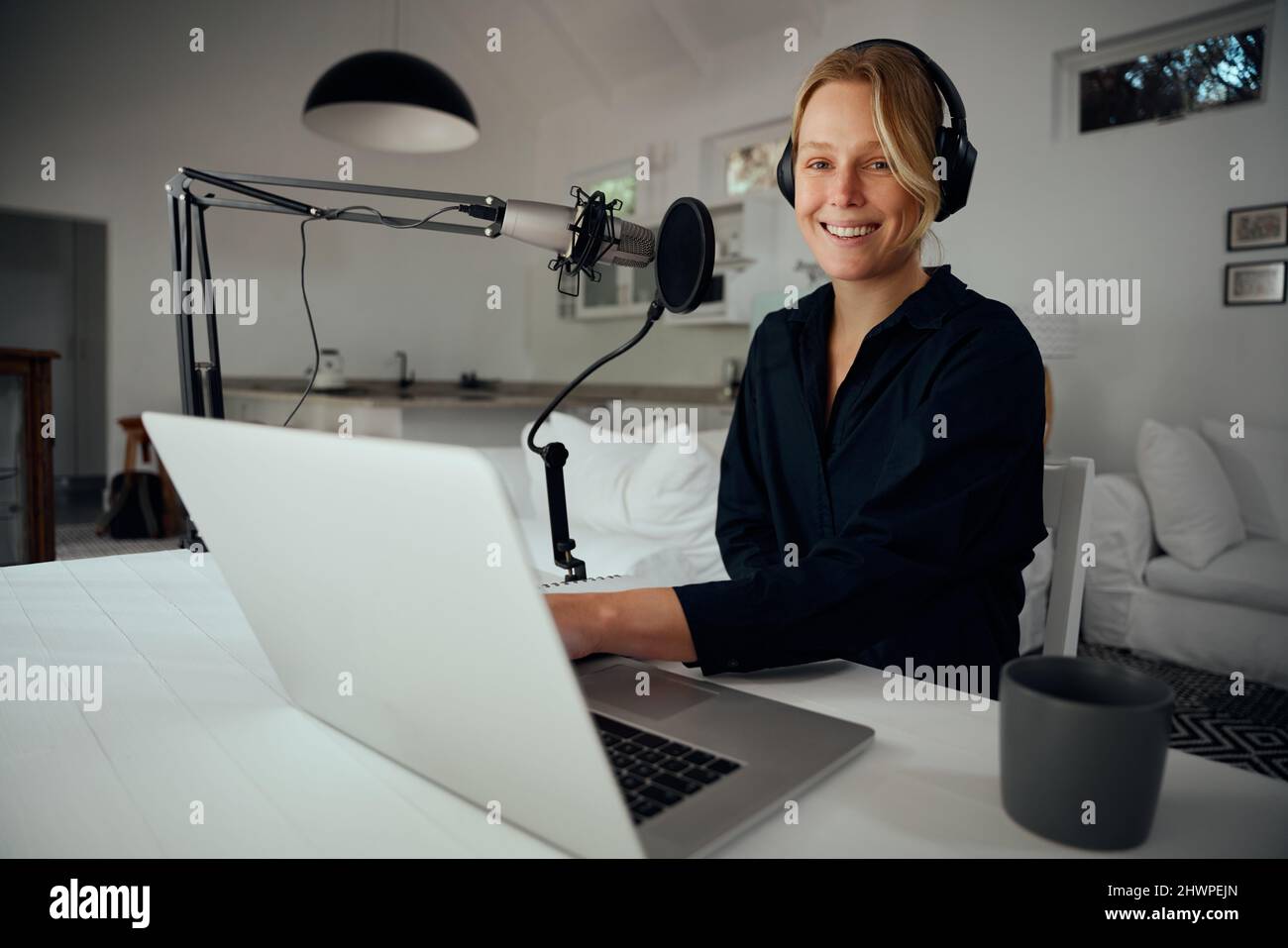 Caucasian female podcaster recording series from home using microphone ...