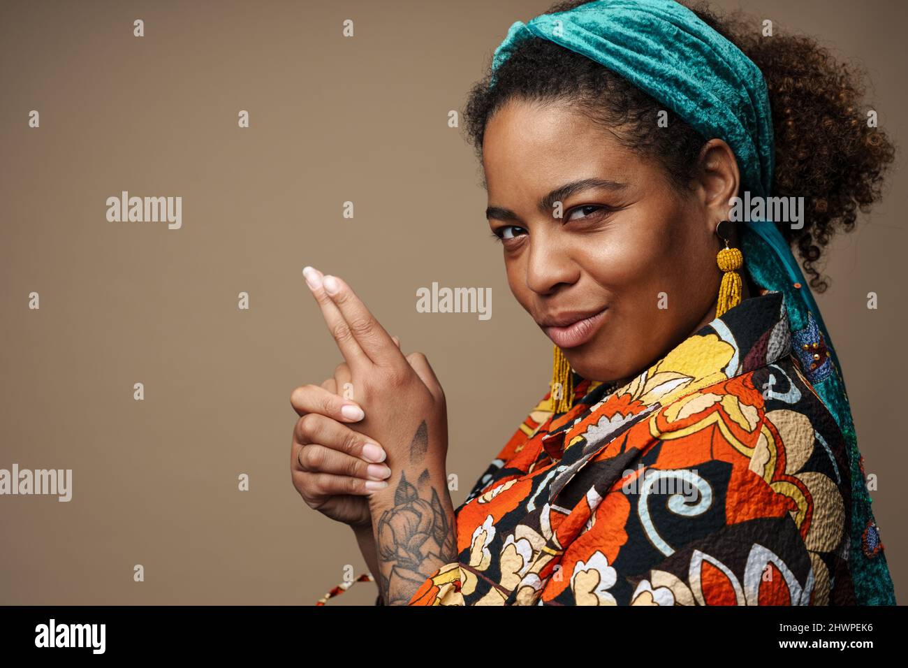 Young black woman smiling while making gun gesture isolated over grey ...