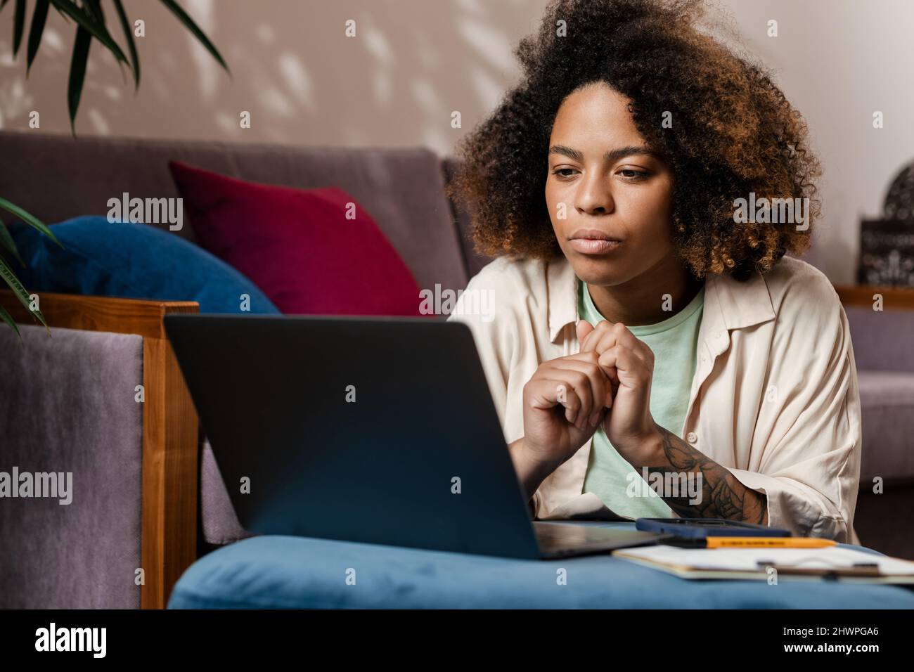 Young black woman using laptop while sitting on floor at home Stock ...