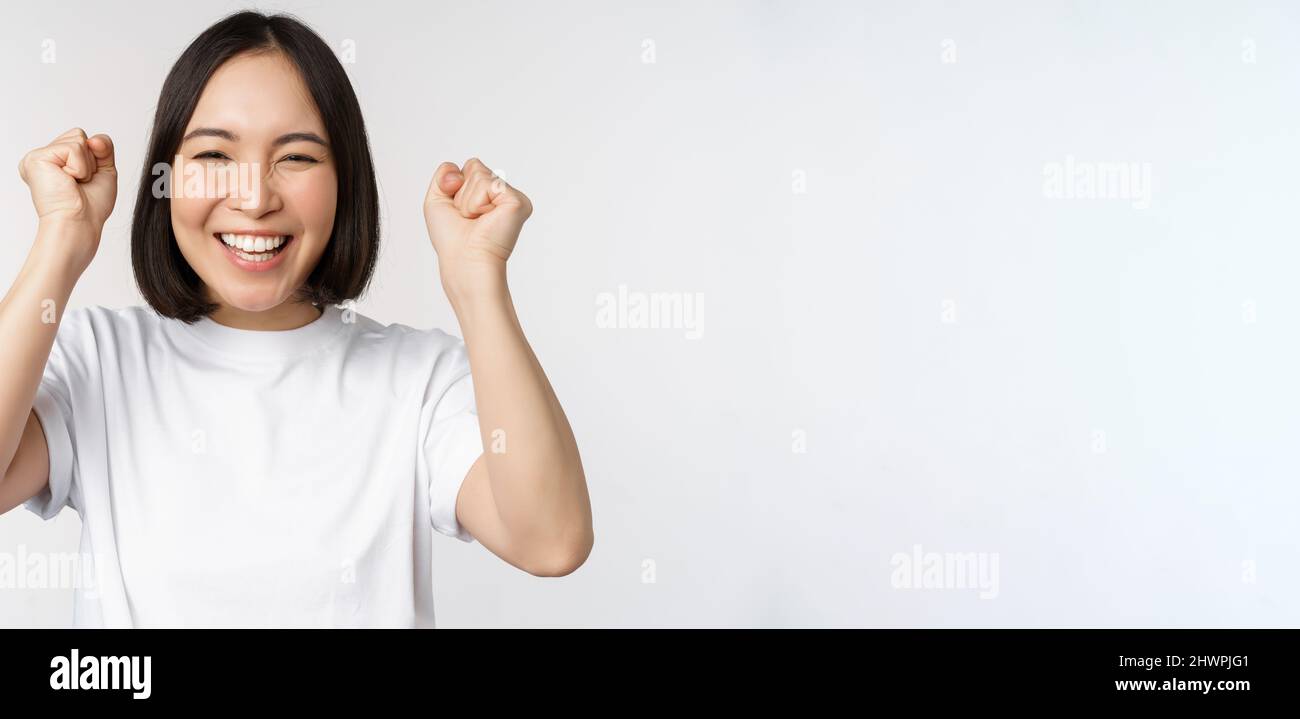 Portrait of enthusiastic asian woman winning, celebrating and ...