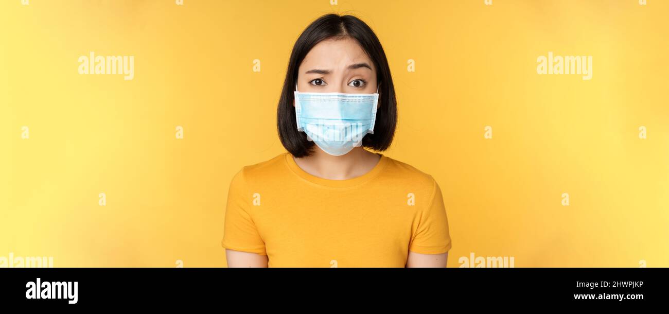 Portrait of skeptical and confused asian woman in medical face mask ...