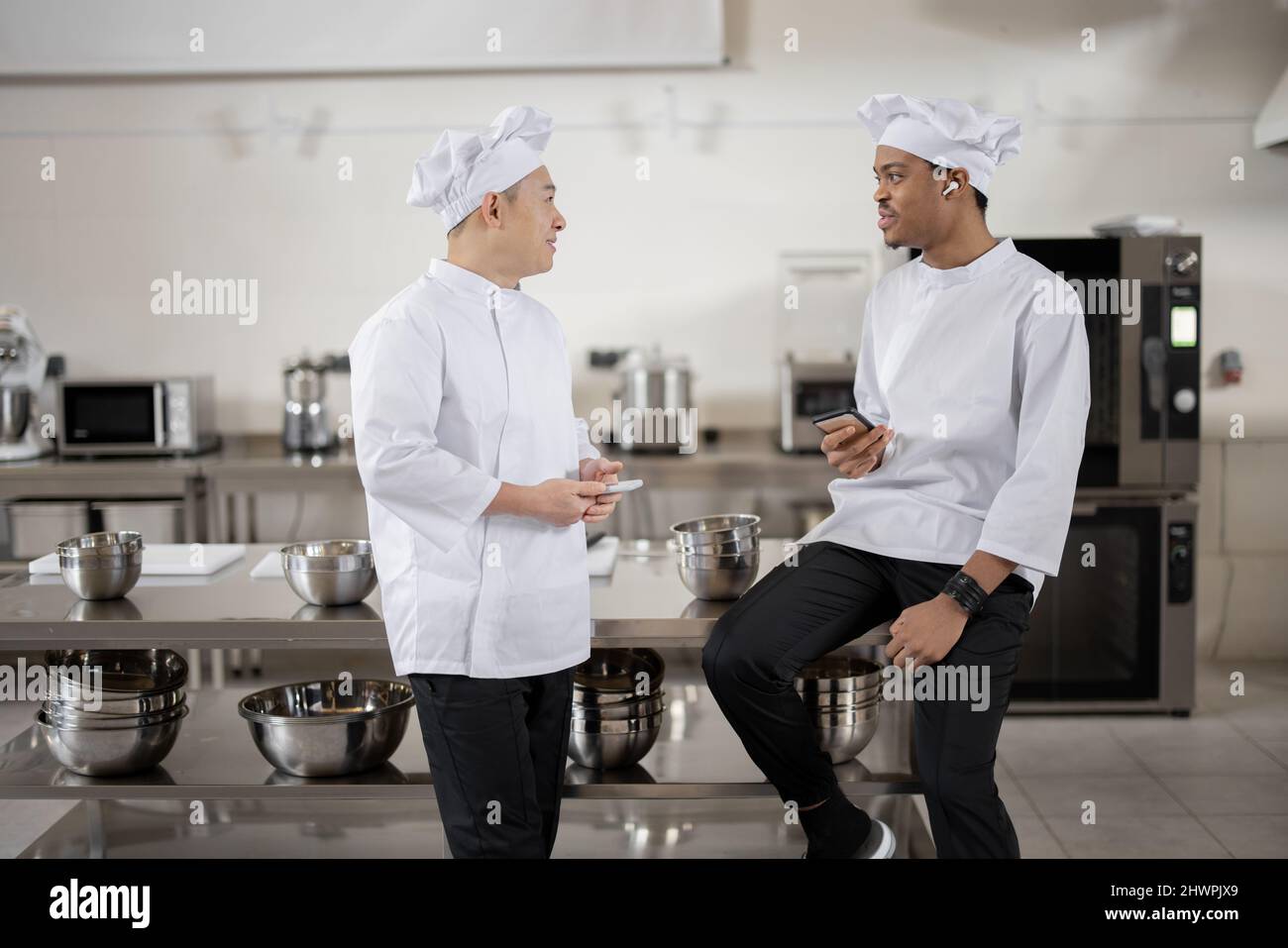 Two multiracial chef cooks talking during a break at the professional ...