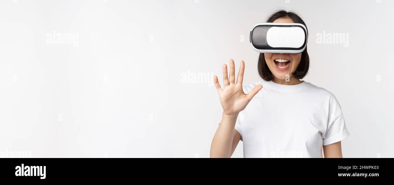 Happy asian woman using VR headset, waving raised hands and laughing ...