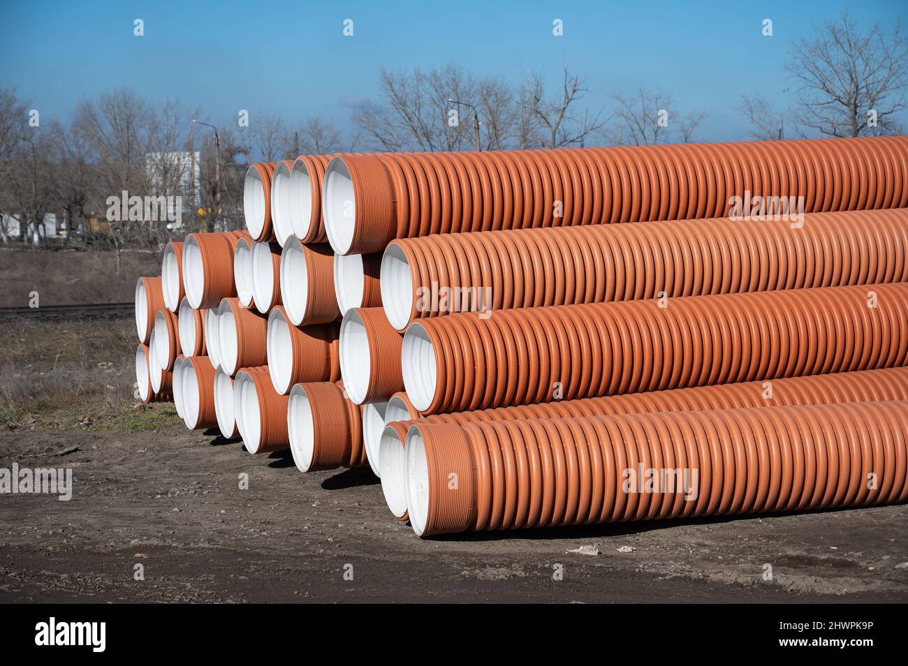 Stack of new orange polypropylene pipes outside. Plastic pipes for ...