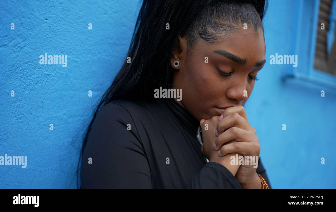 A worried black girl praying to God a pensive preoccupied teenager ...