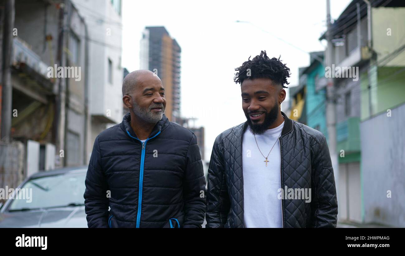 An African father and adult son walking together outside in urban ...