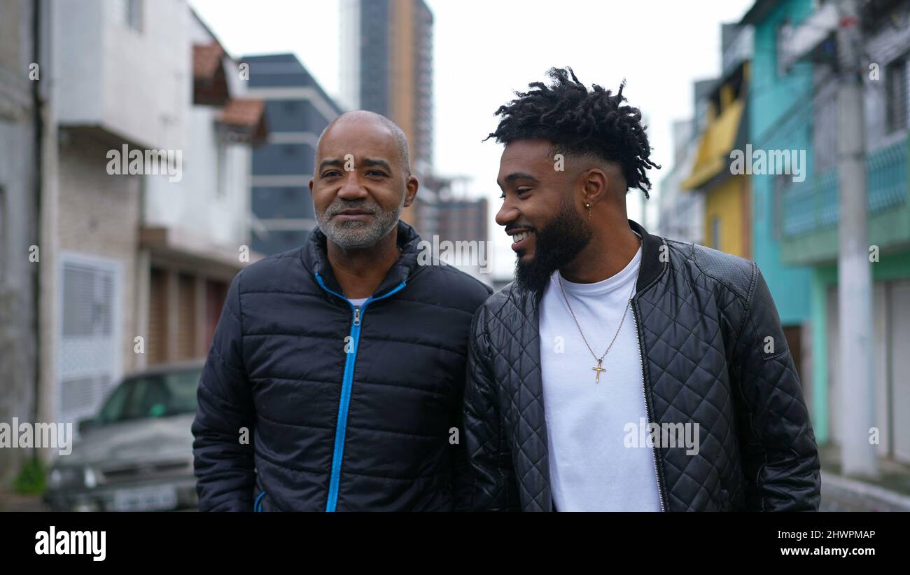An African father and adult son walking together outside in urban ...