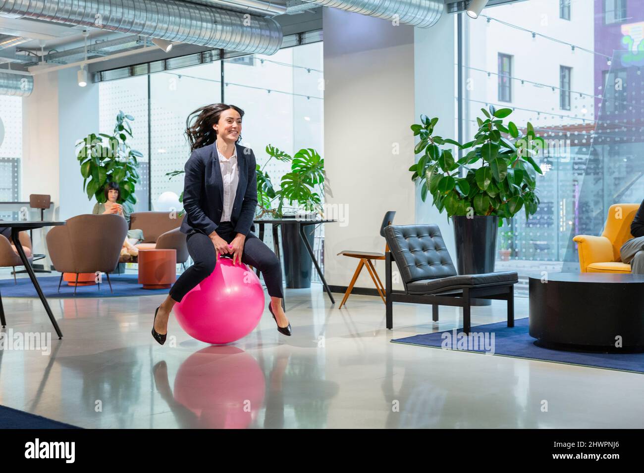 Playful young employee bouncing on hopper ball in office lobby Stock ...