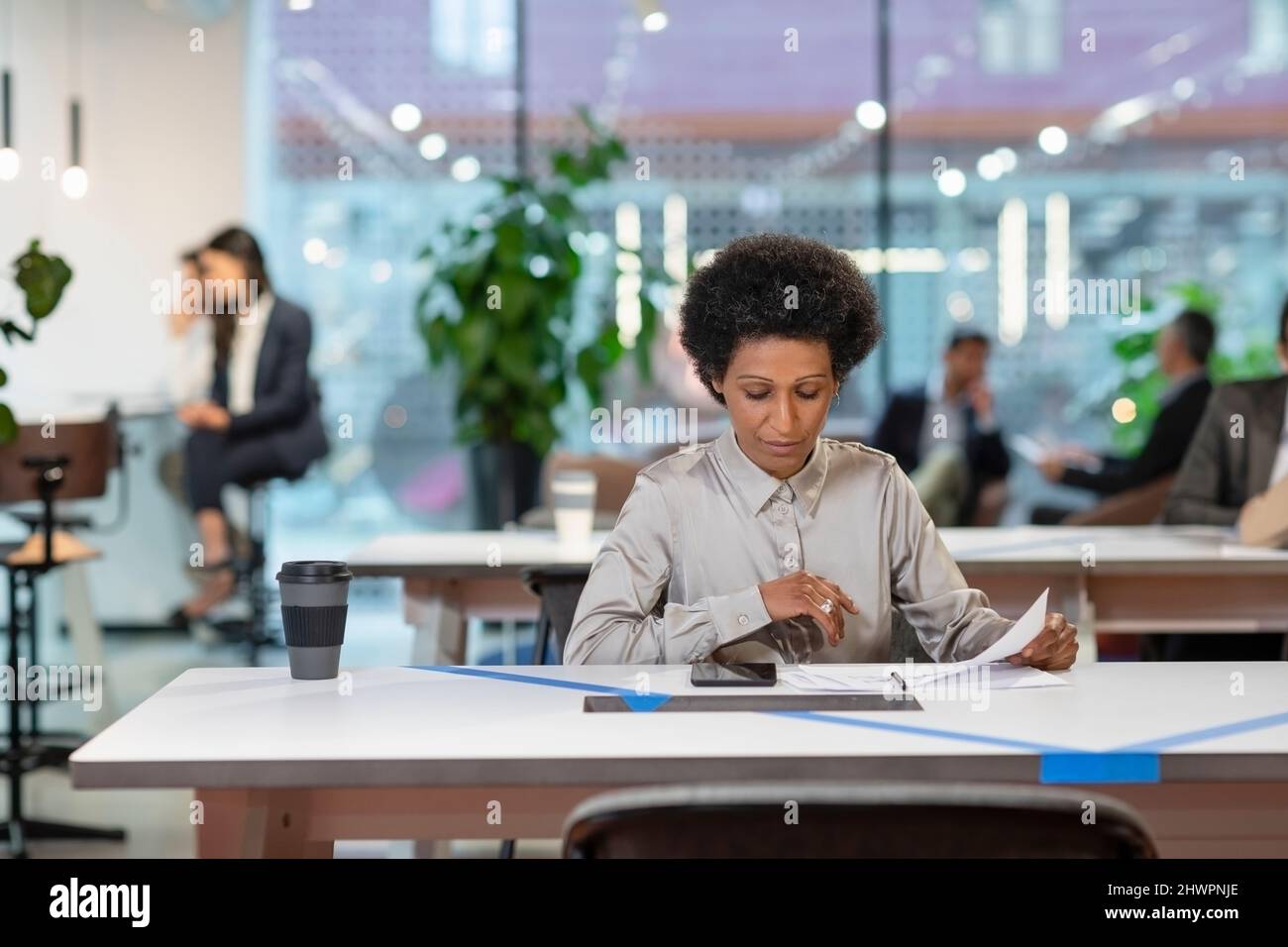 Manager examining over paper document at table in office Stock Photo ...