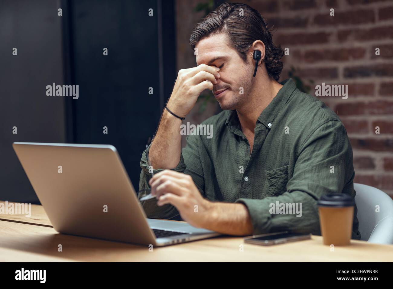 Tensed businessman with laptop sitting at desk in office Stock Photo ...