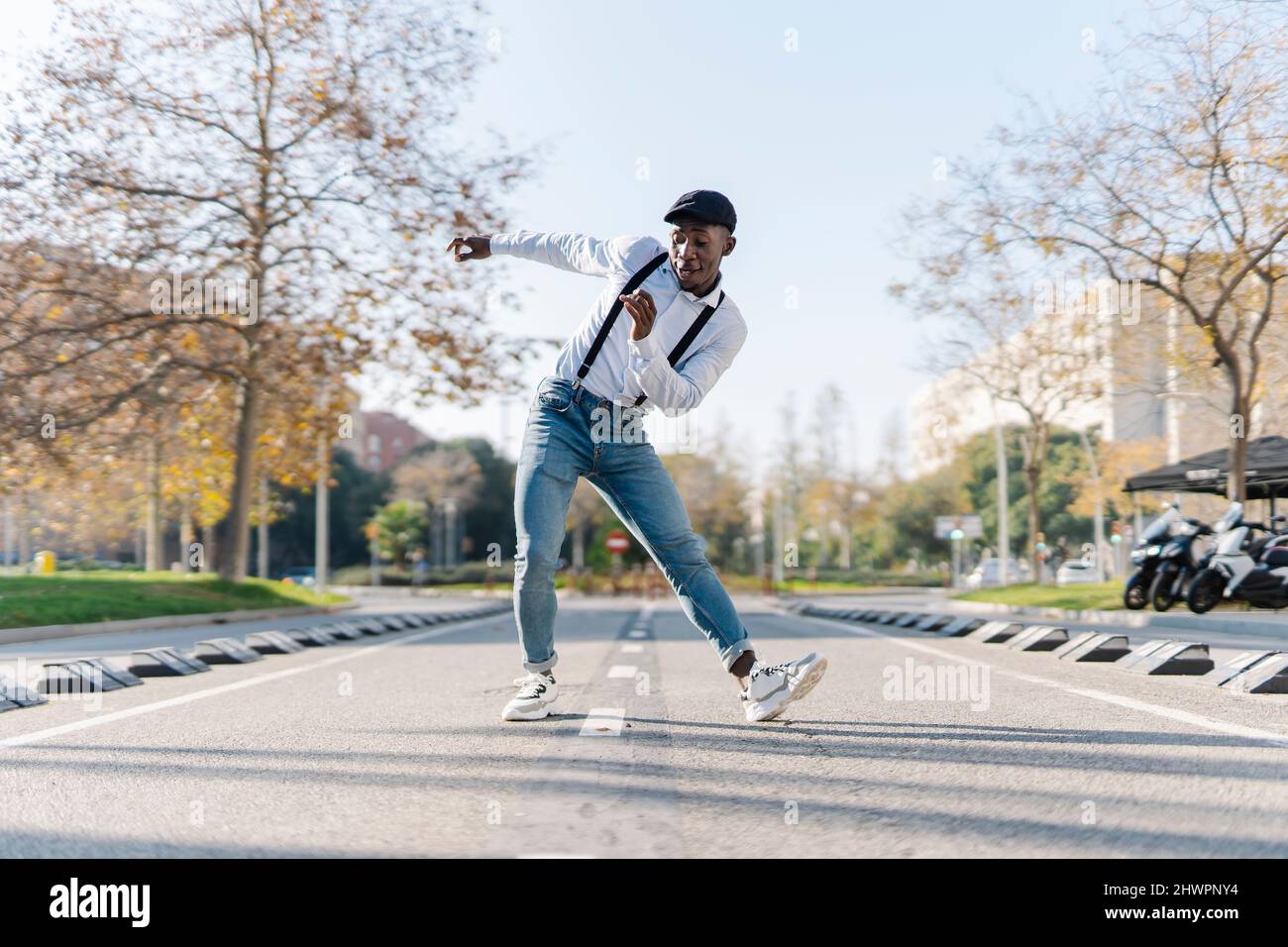 Happy young man wearing cap dancing on city street Stock Photo - Alamy