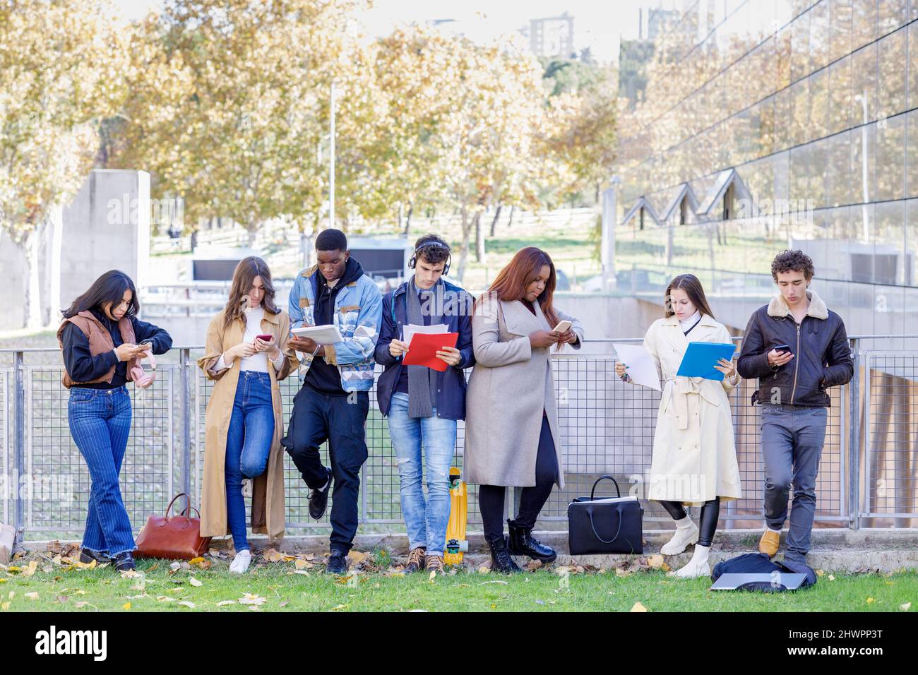 Students studying and using smart phones by railing on campus Stock ...