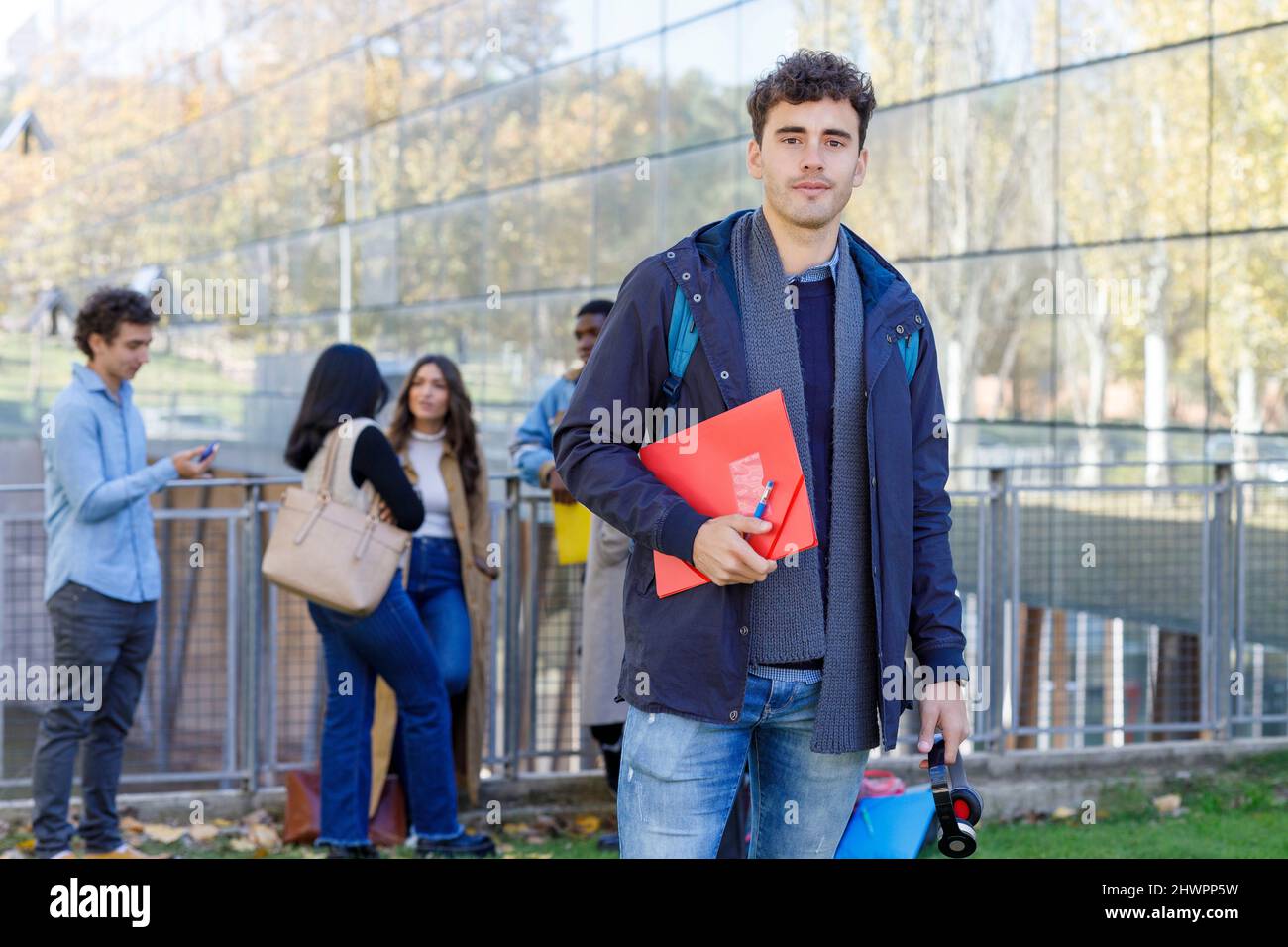 Young man holding file with students in background at campus Stock ...