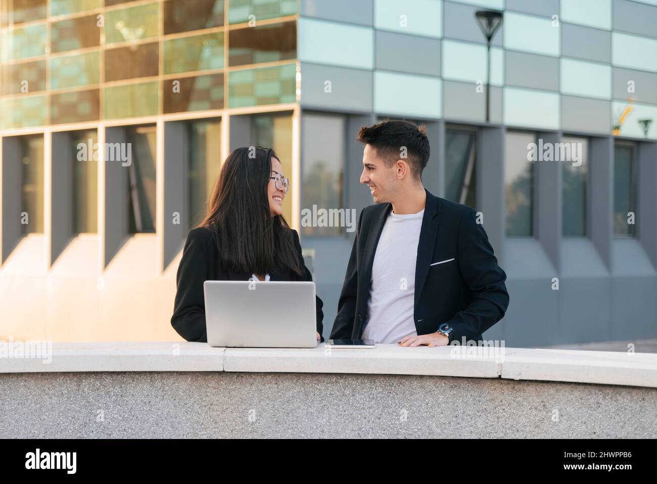 Business colleagues with laptop talking to each other behind wall Stock ...