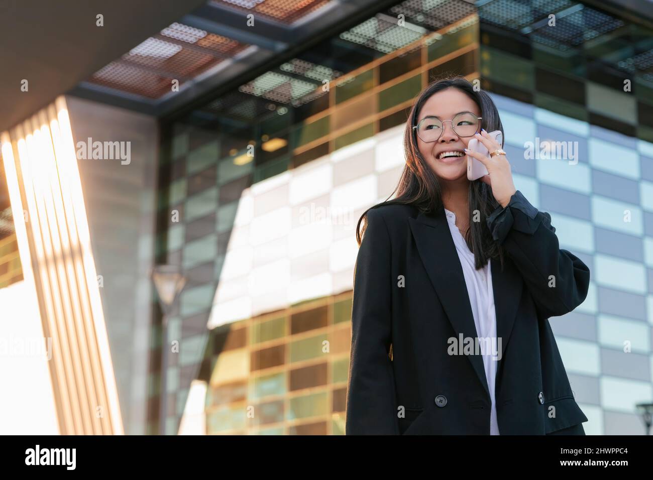 Young businesswoman talking on mobile phone in front of office building Stock Photo - Alamy