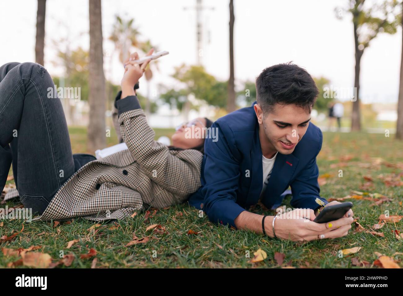 Young business colleagues using smart phones lying in public park Stock ...