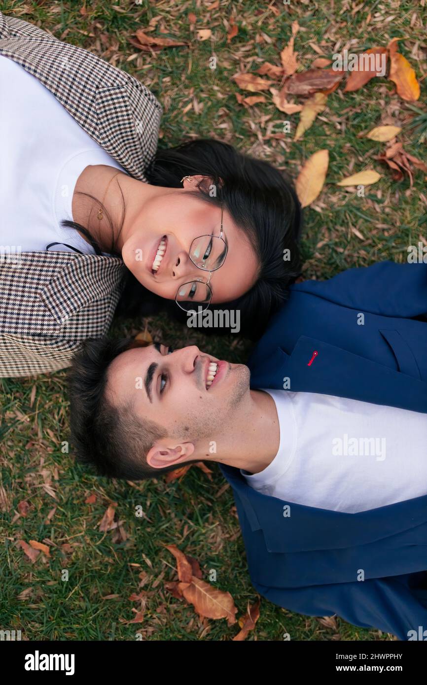 Business colleagues looking at each other lying on grass Stock Photo ...