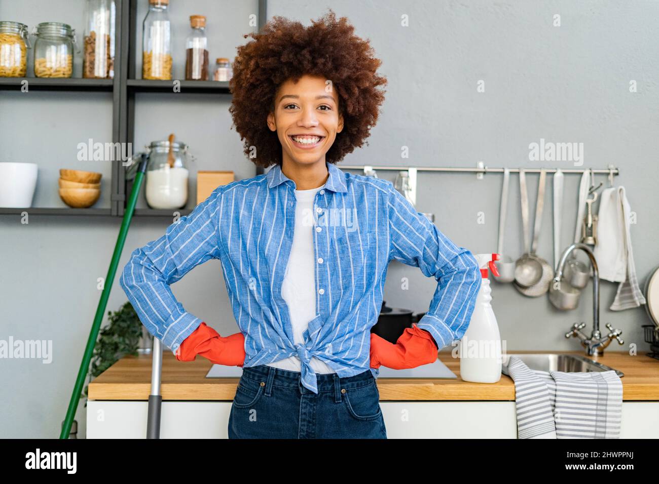 Cheerful young Afro woman standing with arms akimbo in kitchen Stock ...
