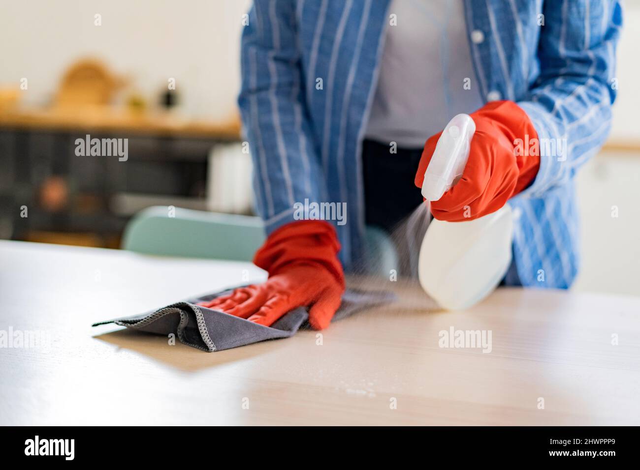 Woman spraying disinfection on dining table in kitchen Stock Photo - Alamy