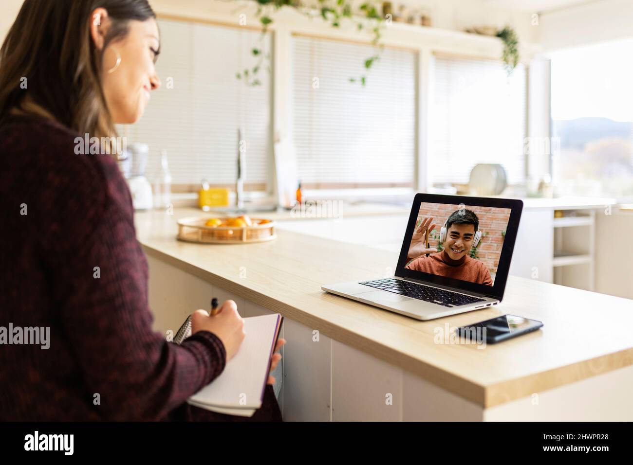 Businesswoman doing video call with colleague on laptop at home Stock ...