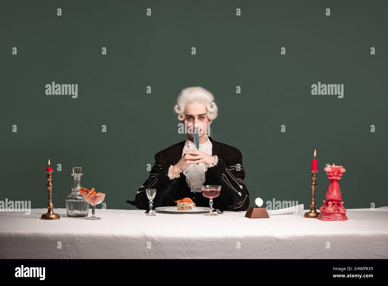 Portrait of young elegant man in peruke and vintage jacket sitting at ...