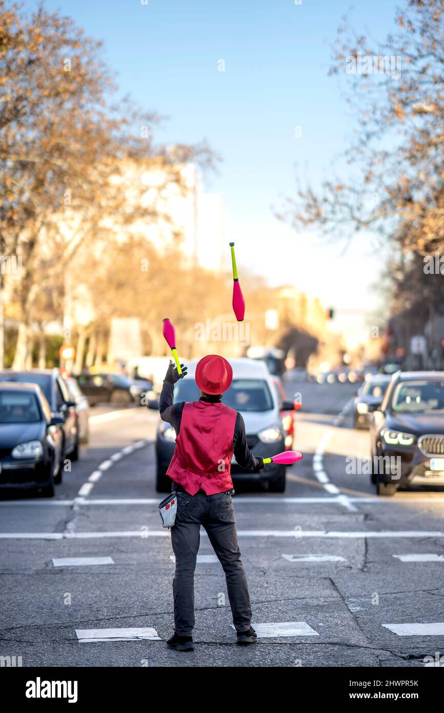 Solo performer juggling pins in front of cars on street Stock Photo - Alamy