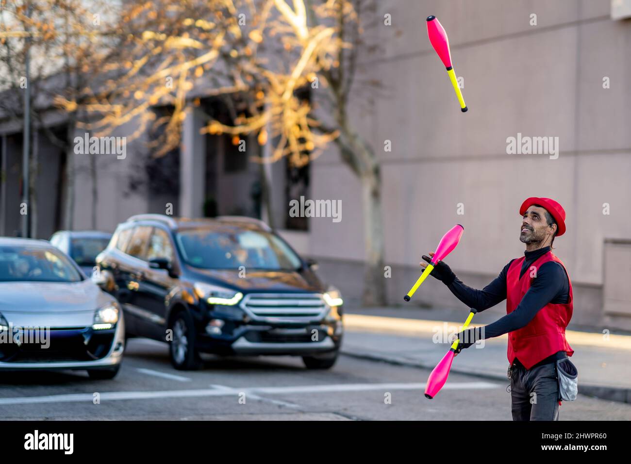 Street artist juggling pins in front of cars Stock Photo - Alamy
