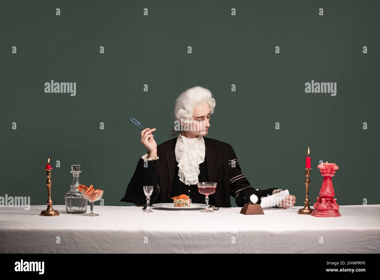 Portrait of young elegant man in peruke and vintage jacket sitting at ...