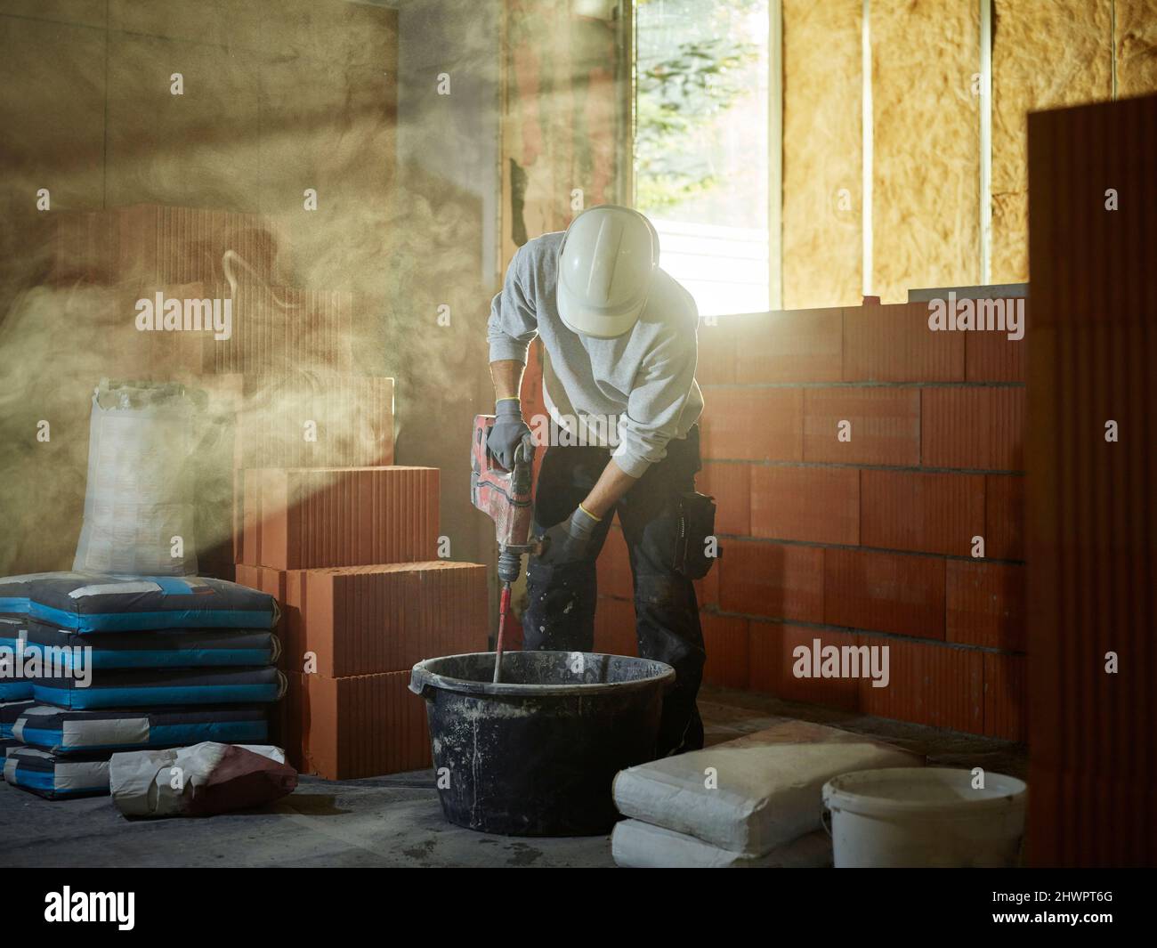 Bricklayer mixing cement in tub at construction site Stock Photo - Alamy