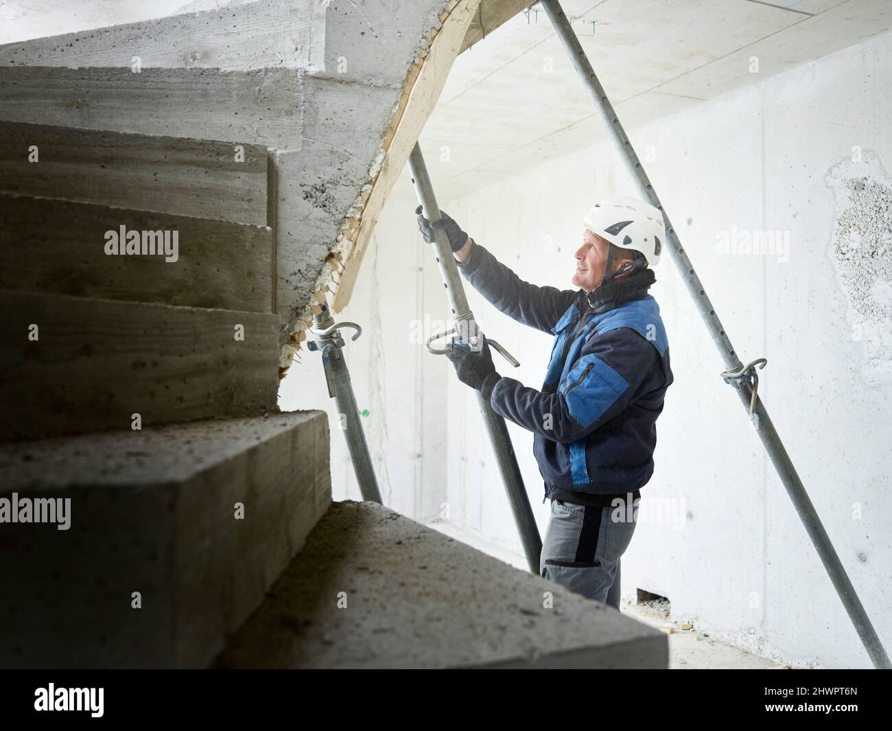 Worker unscrewing support poles by stairs at construction site Stock ...