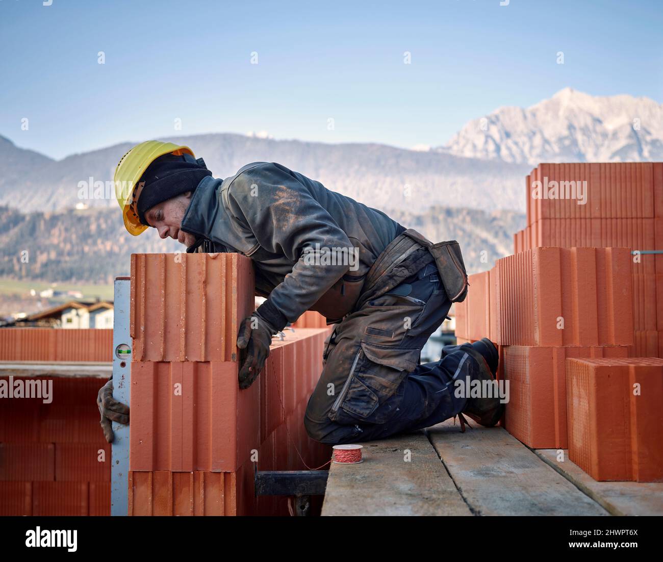 Bricklayer measuring bricks with tool at construction site Stock Photo ...