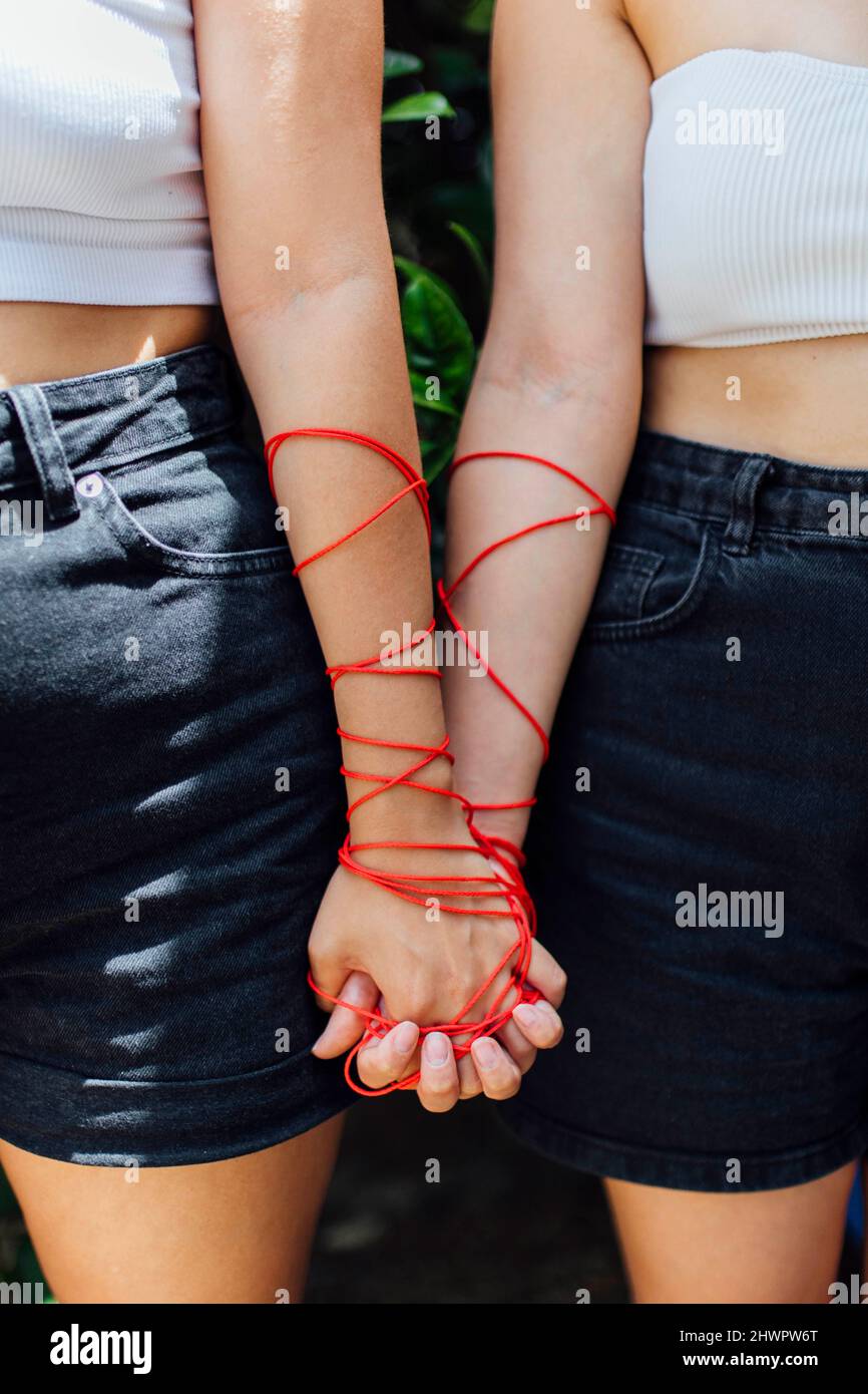 Two women with thread holding hands Stock Photo - Alamy