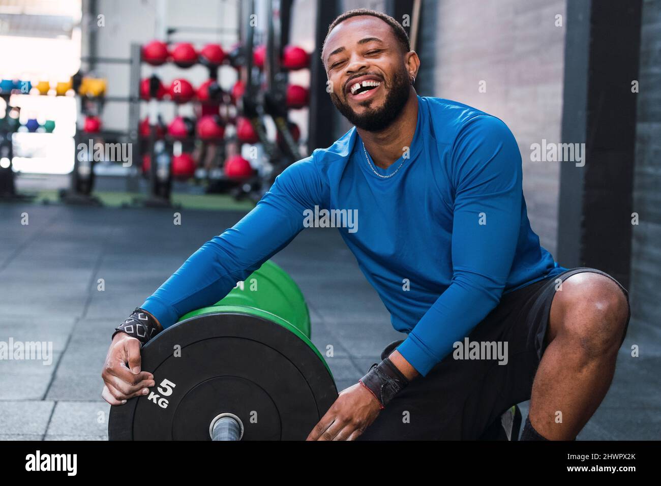 Happy athlete putting weights in barbell at gym Stock Photo - Alamy