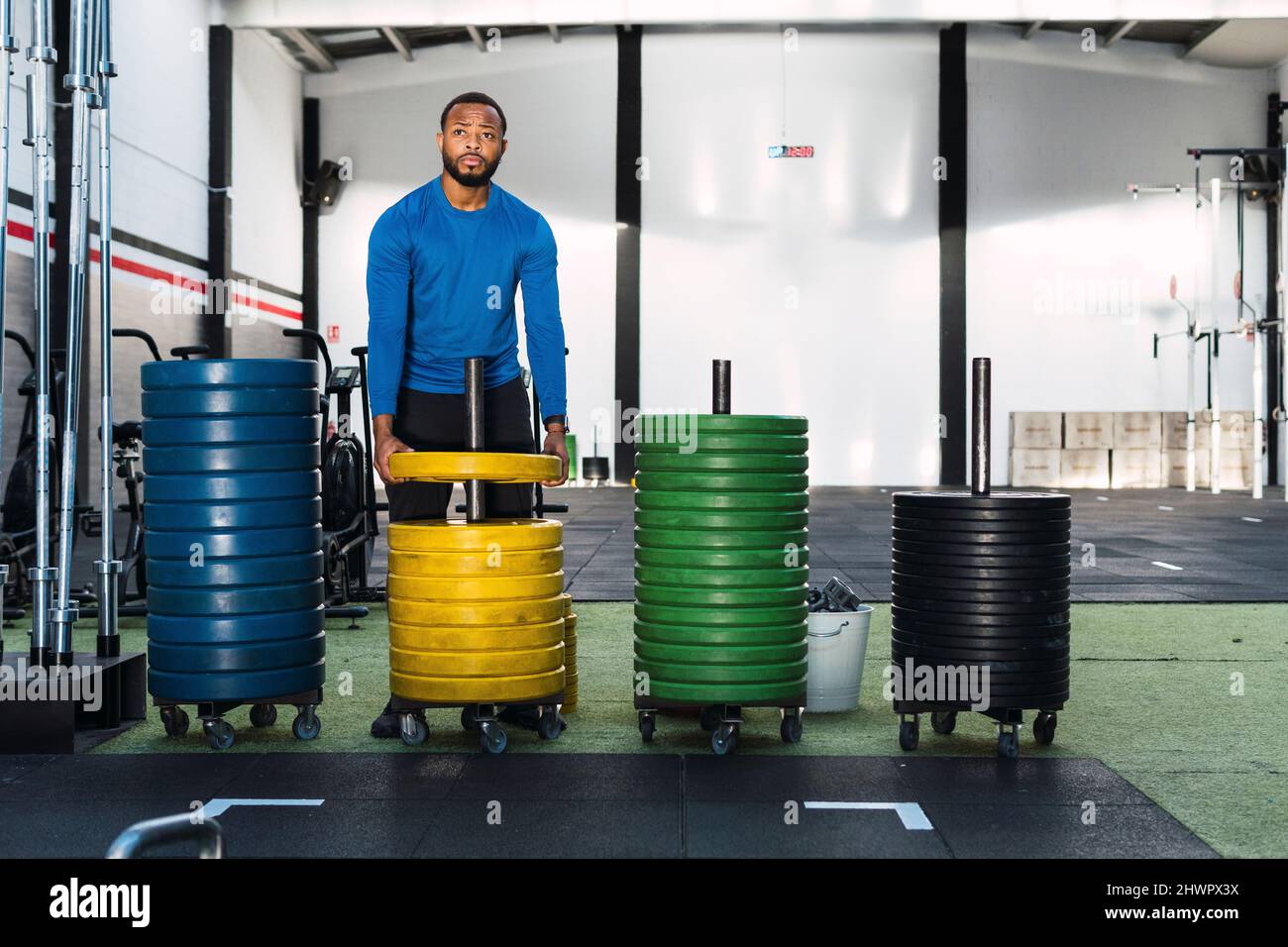 Young athlete standing near weight plates in gym Stock Photo - Alamy